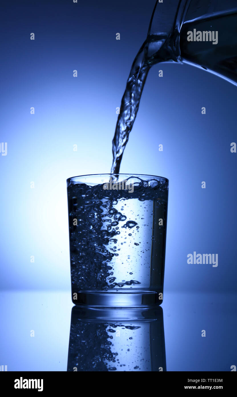 Pour water from pitcher into glass, on dark blue background Stock Photo ...