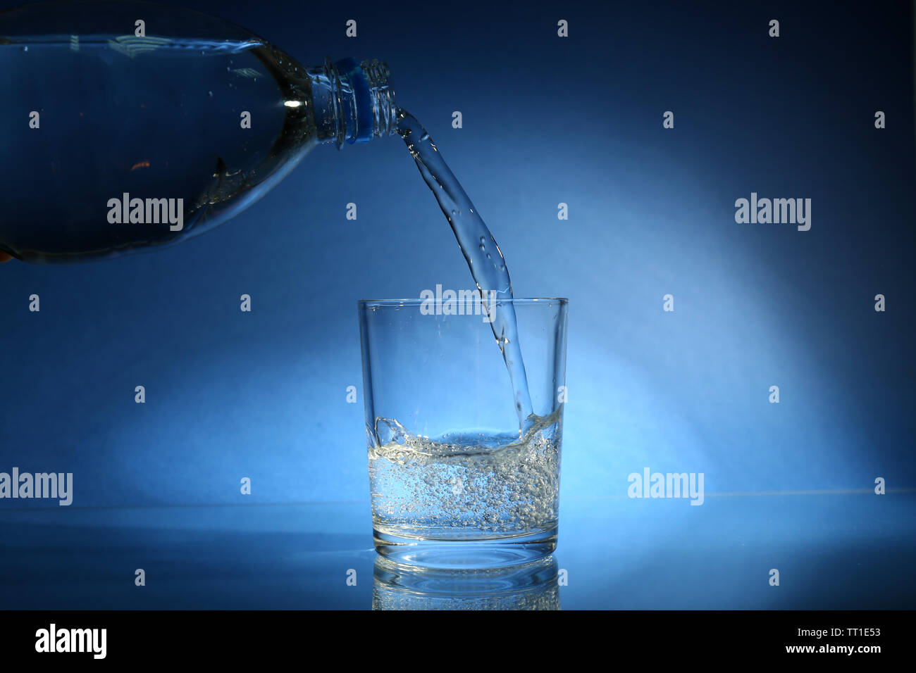 Pour water from bottle into glass, on dark blue background Stock Photo ...
