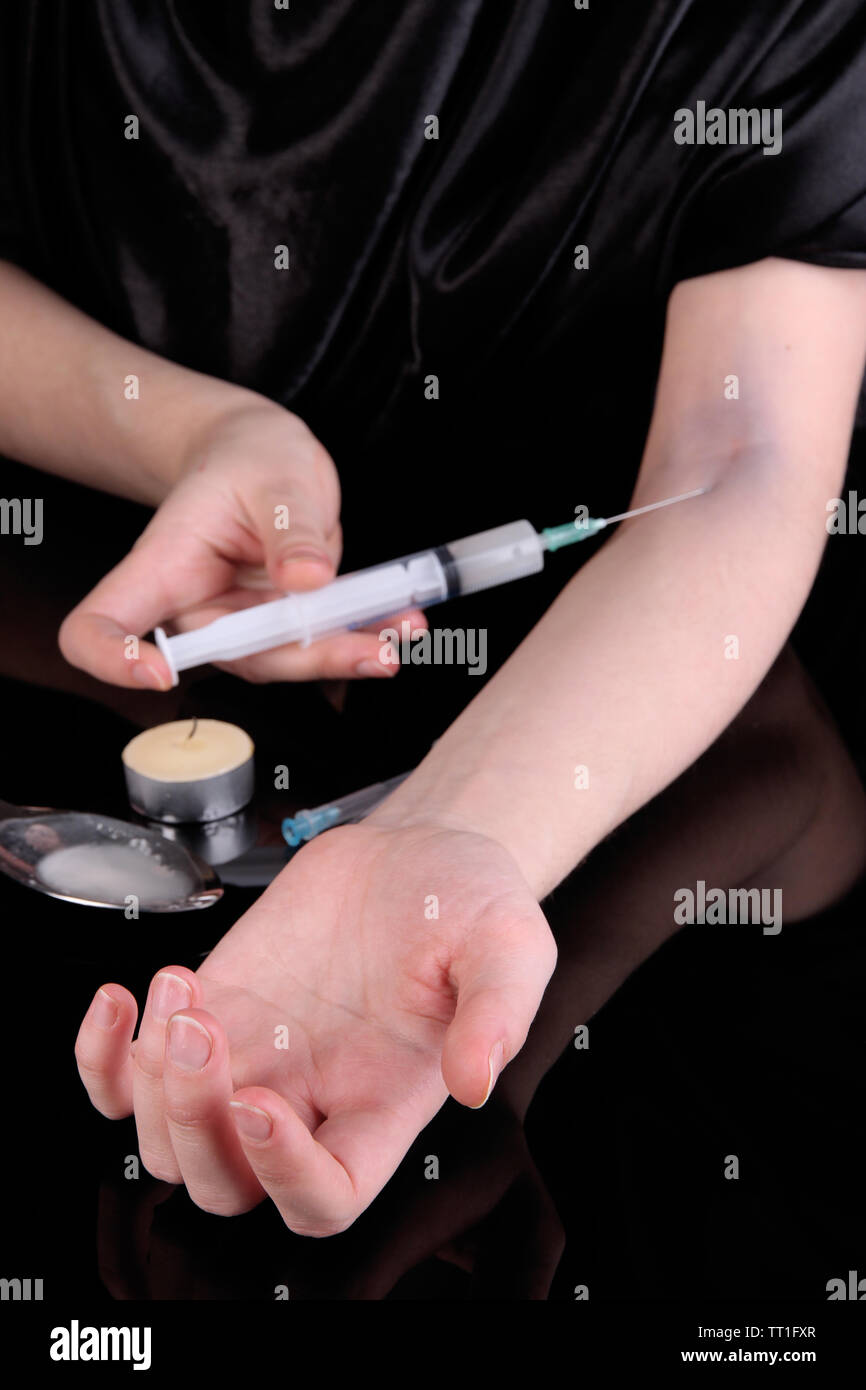Drug addict with syringe in action on black background Stock Photo - Alamy