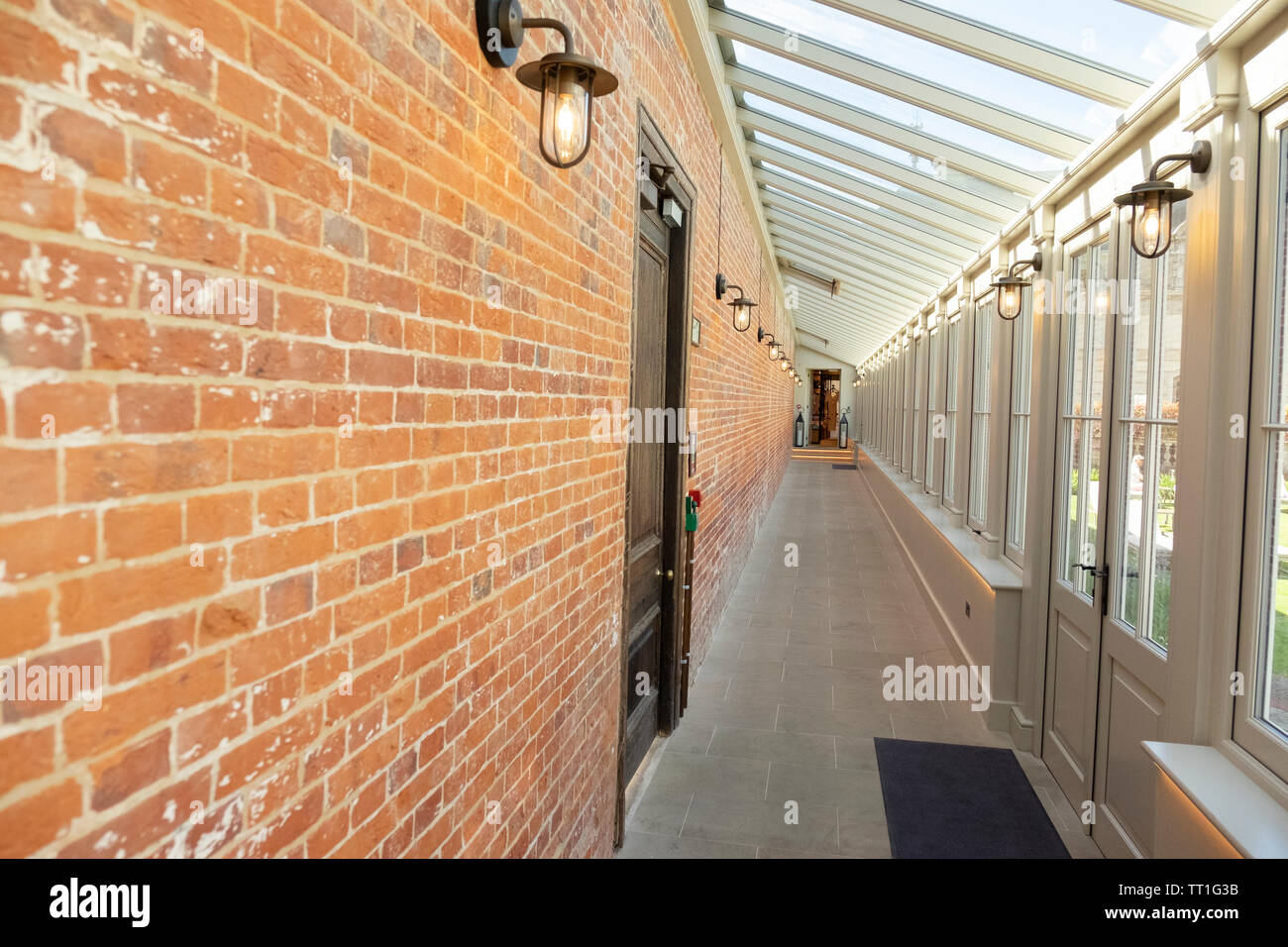 Long straight corridor with brick wall on one side, windows on the ...