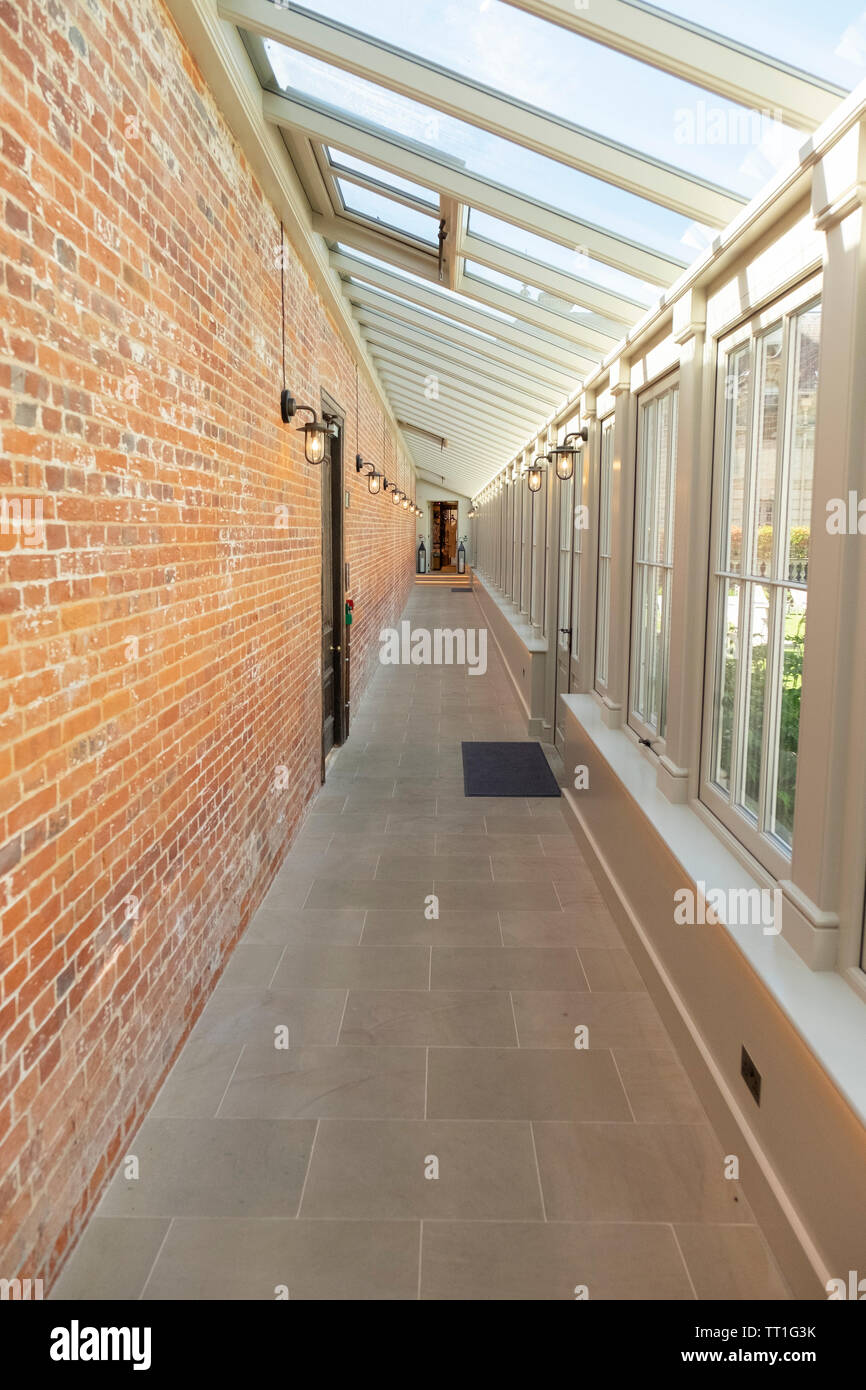Long straight corridor with brick wall on one side, windows on the ...