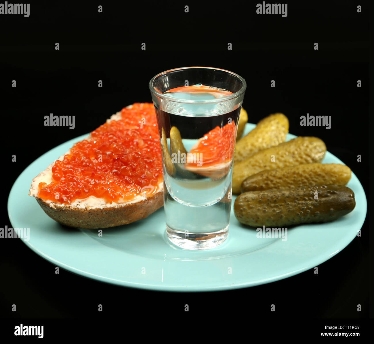 Composition with glass of vodka and snacks on color plate, isolated on ...