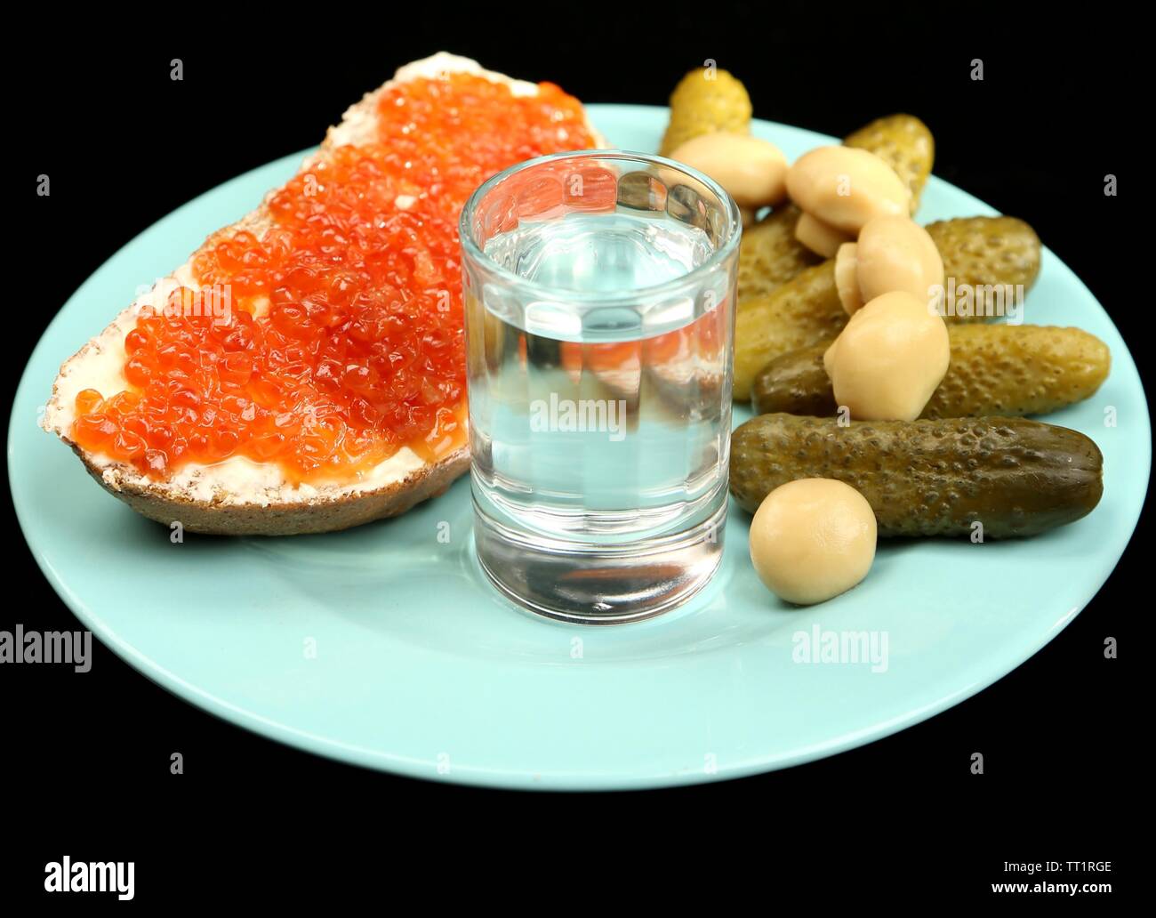Composition with glass of vodka and snacks on color plate, isolated on ...