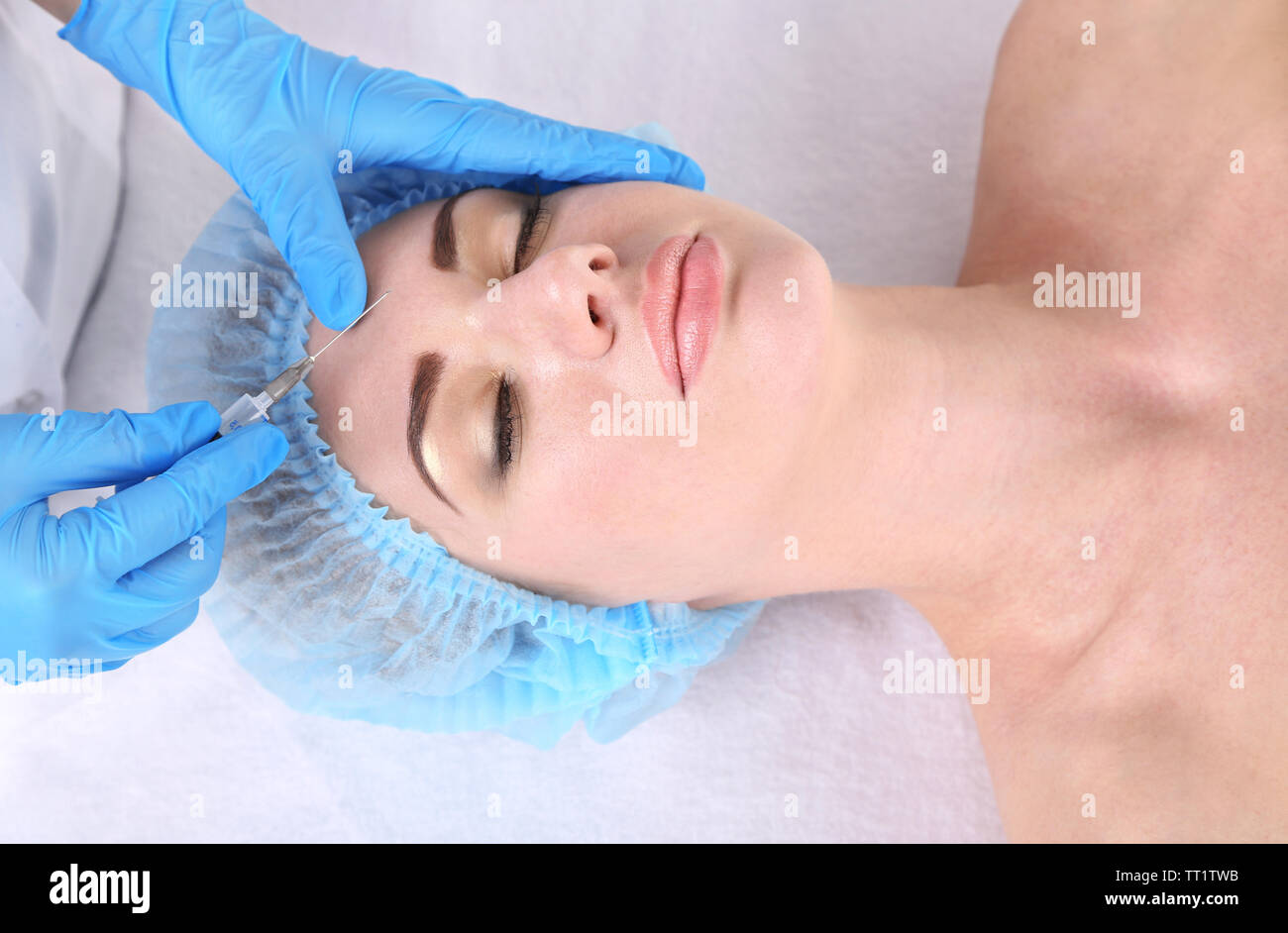 Woman in beauty clinic getting botox injection, on light background ...