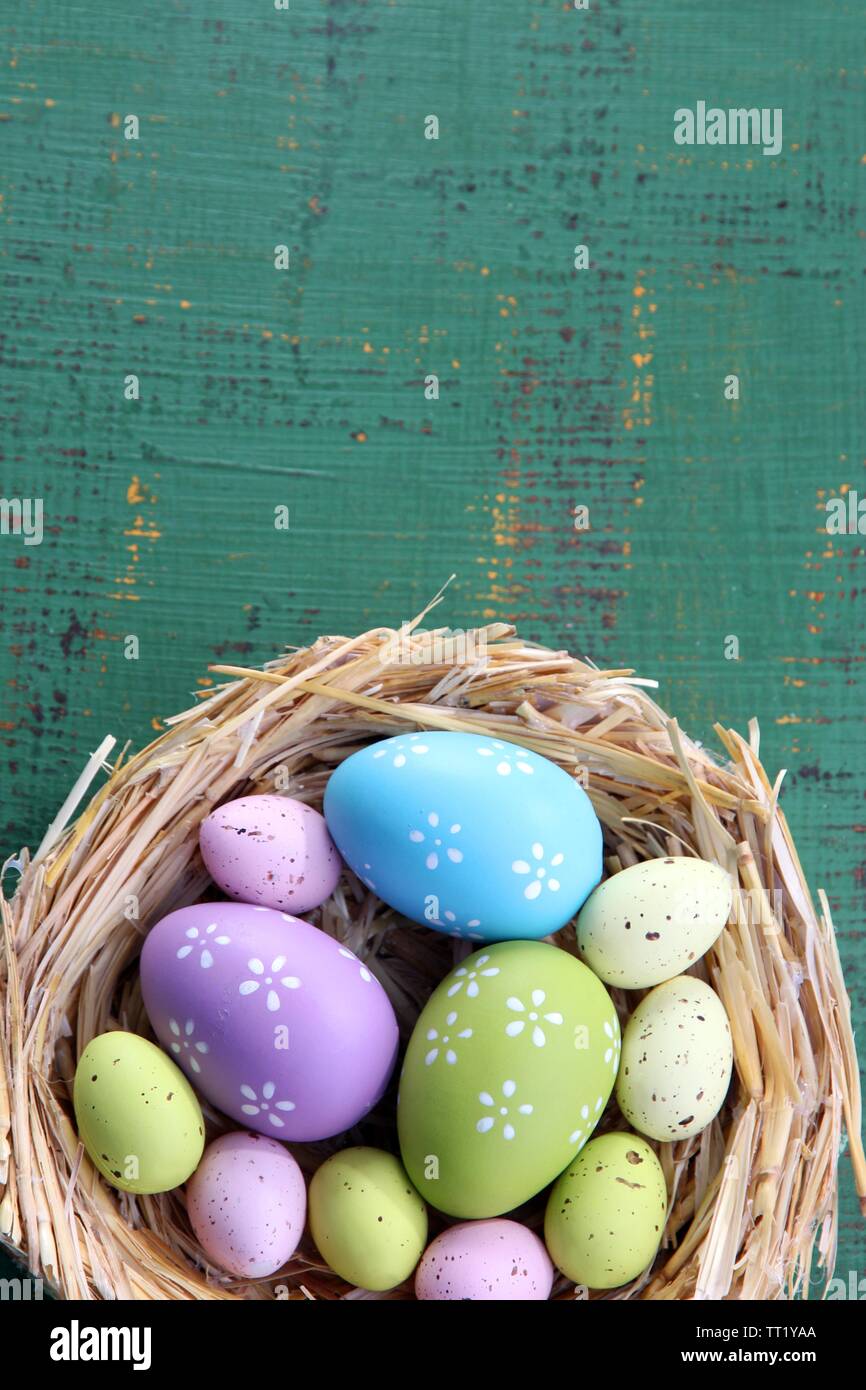 Easter eggs in nest on color wooden background Stock Photo - Alamy