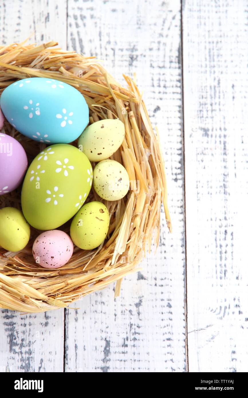 Easter eggs in nest on color wooden background Stock Photo - Alamy
