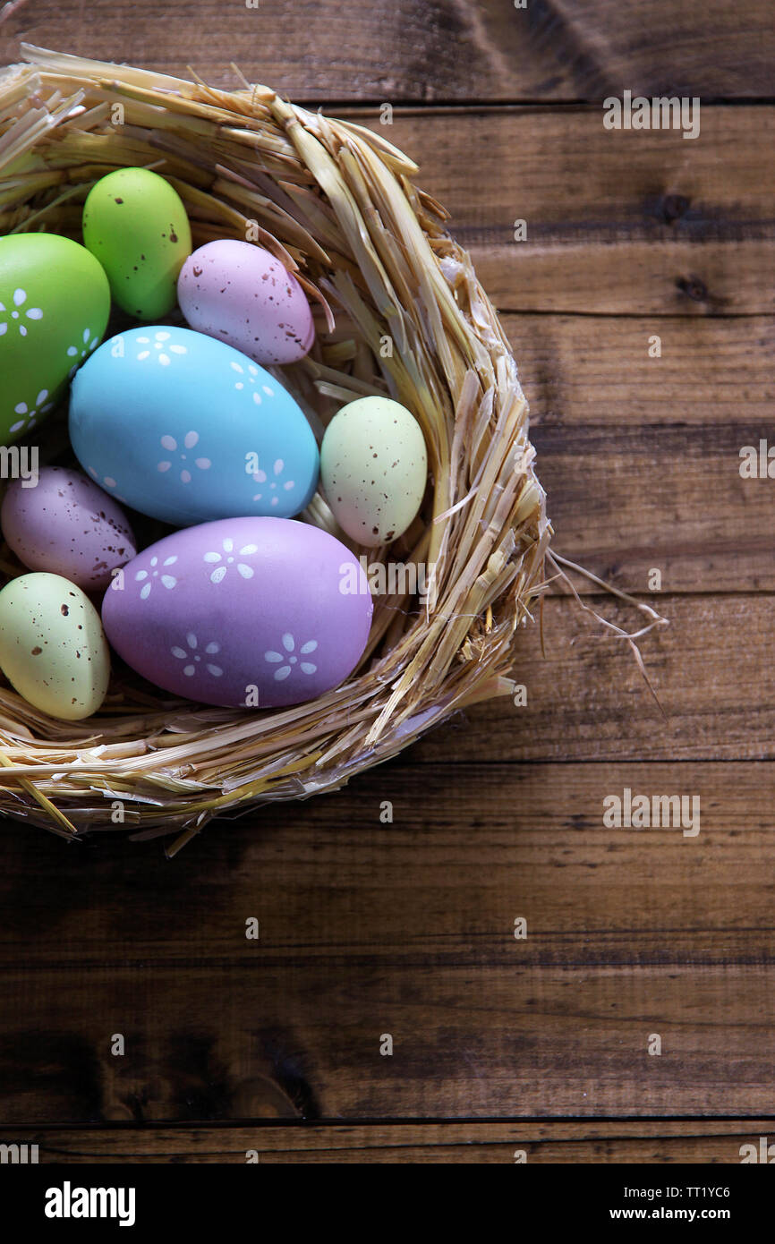 Easter eggs in nest on color wooden background Stock Photo - Alamy