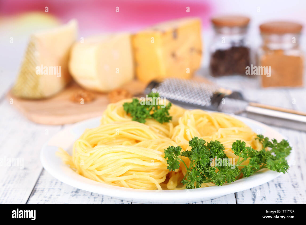 Composition with tasty spaghetti, grater, cheese, and spices on wooden ...