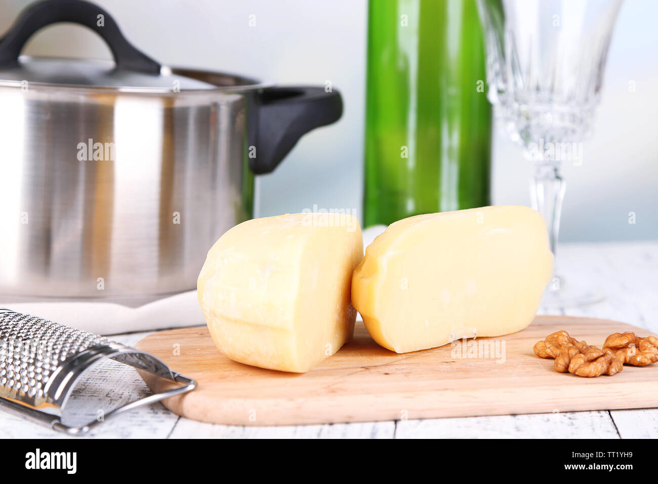 Composition with prepared spaghetti in pan, grater, cheese, wine bottle ...