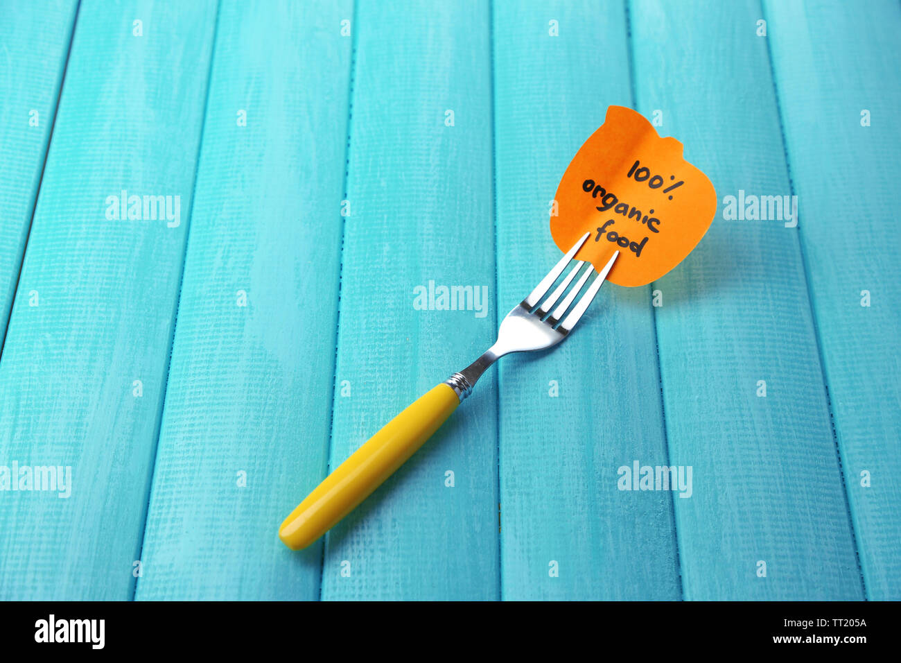 Note paper with message attached to fork, on plate, on color wooden ...