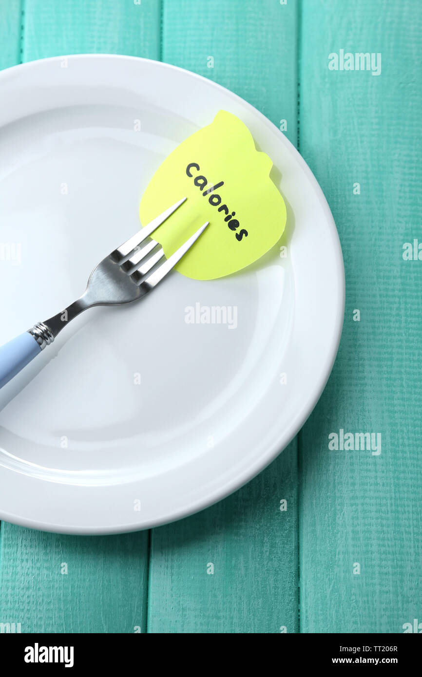 Note paper with message attached to fork, on plate, on wooden ...