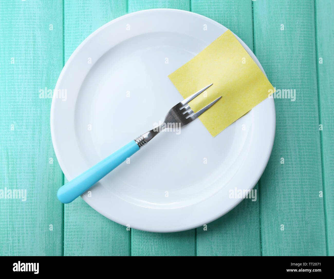 Empty note paper attached to fork, on plate, on color wooden background ...