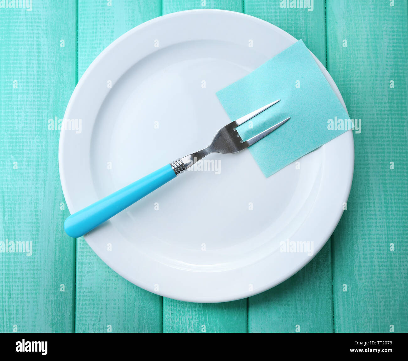 Empty note paper attached to fork, on plate, on color wooden background ...