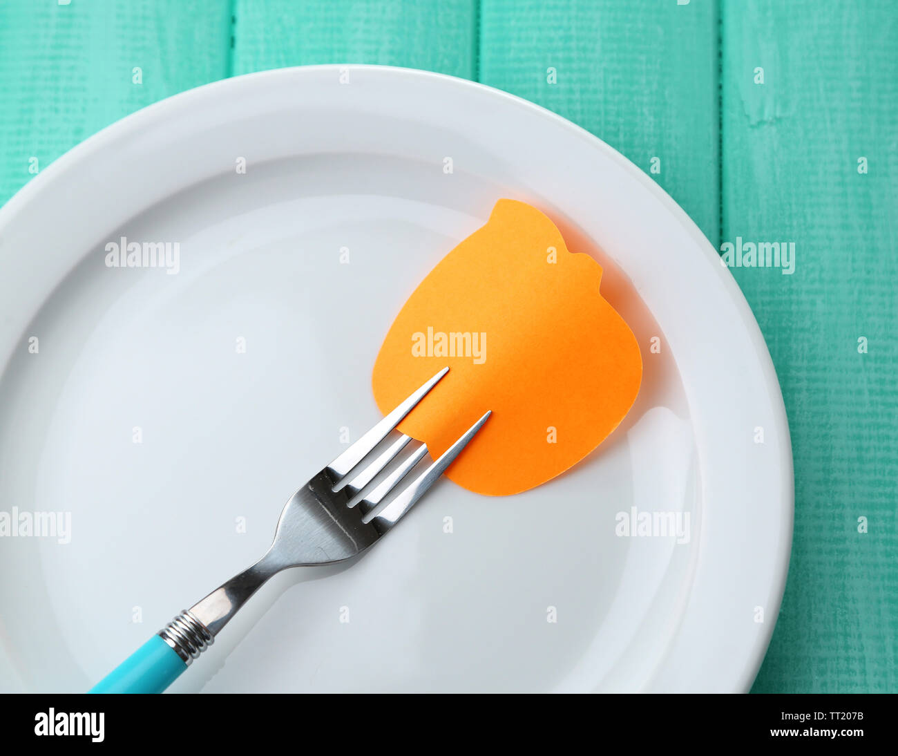 Empty note paper attached to fork, on plate, on color wooden background ...