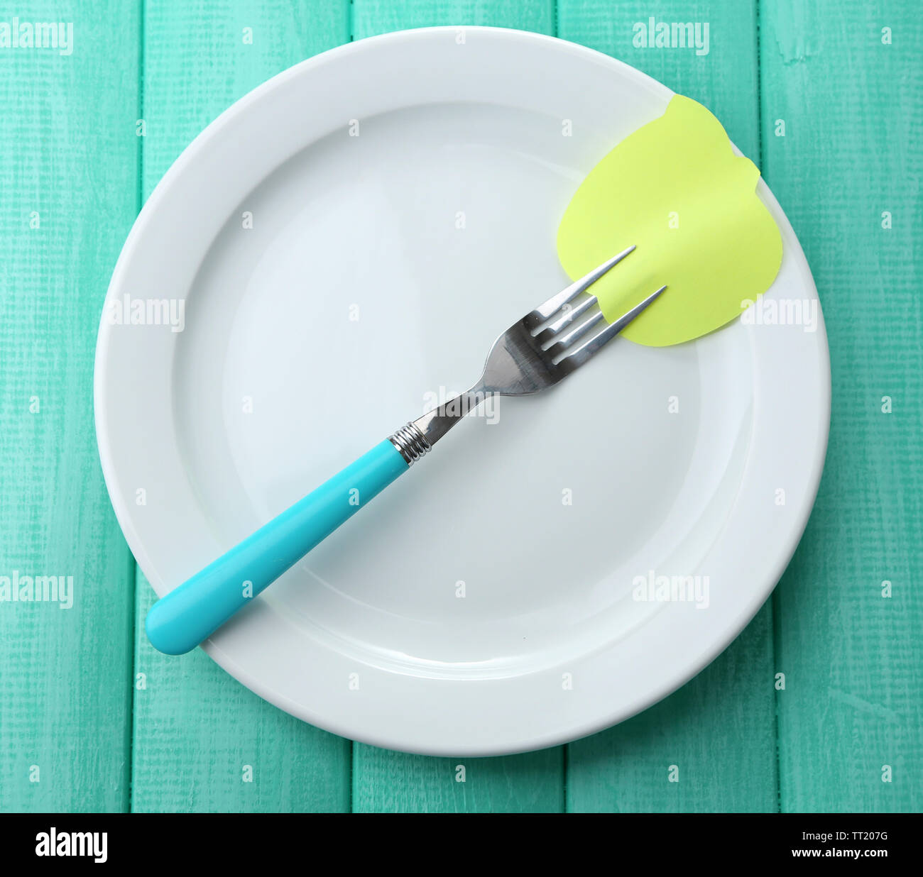 Empty note paper attached to fork, on plate, on color wooden background ...