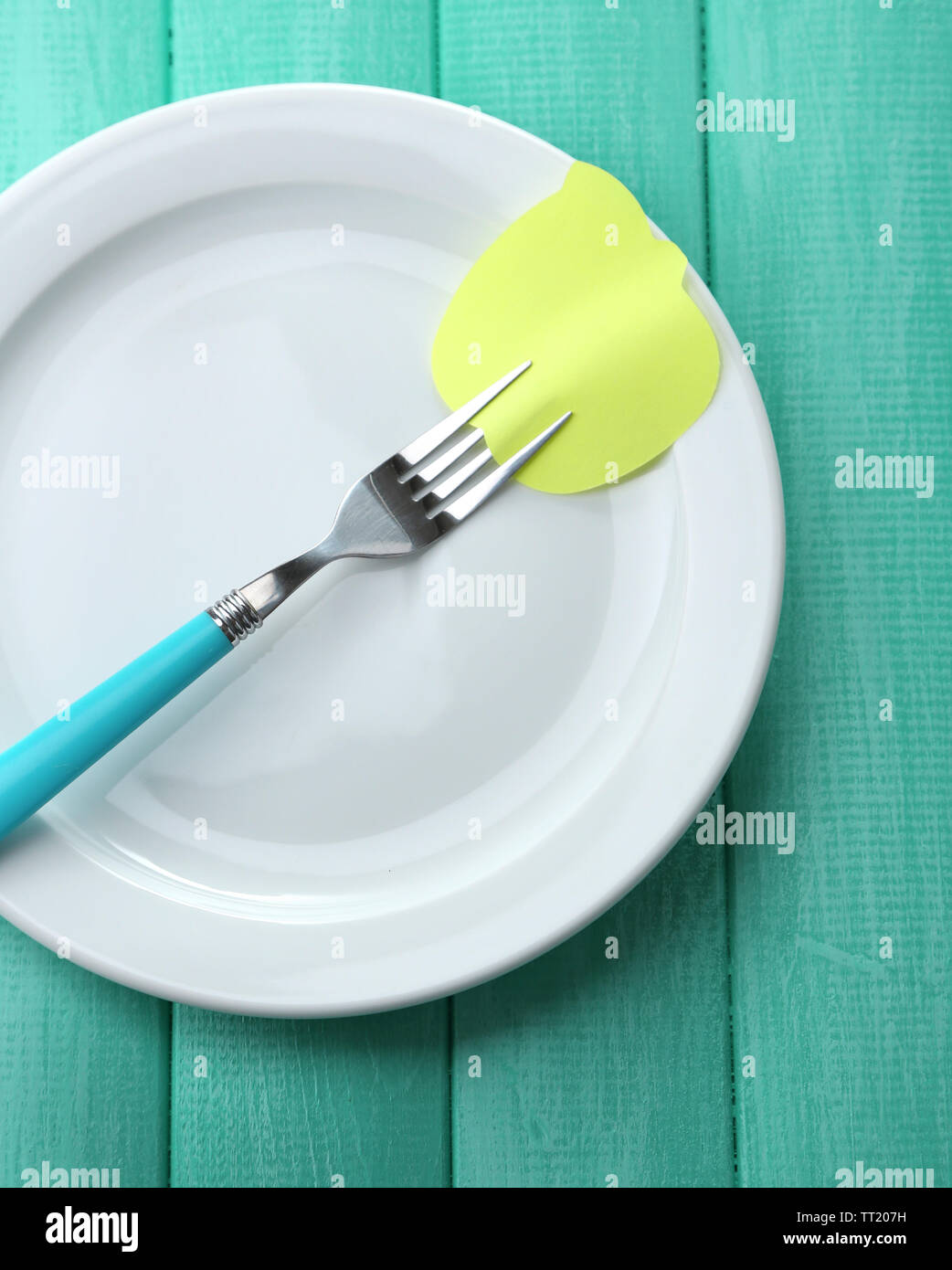 Empty note paper attached to fork, on plate, on color wooden background ...