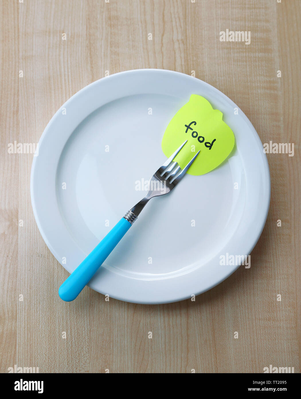 Note paper with message attached to fork, on plate, on color wooden ...