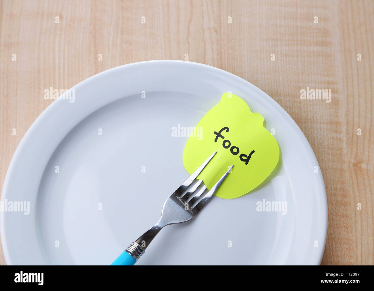Note paper with message attached to fork, on plate, on color wooden ...