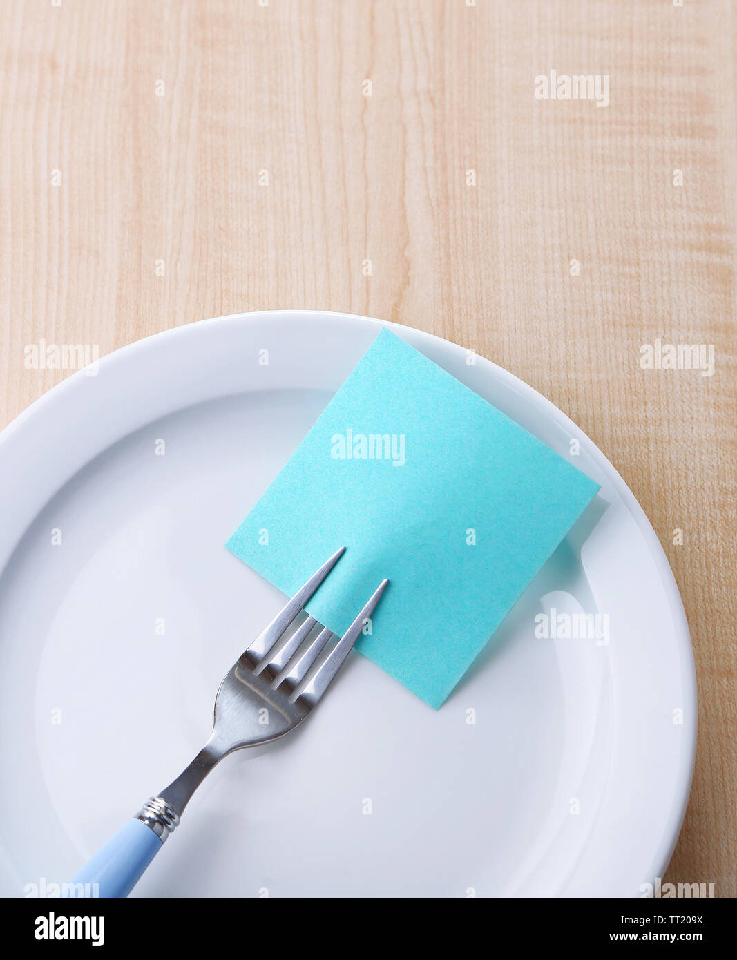 Empty note paper attached to fork, on plate, on color wooden background ...