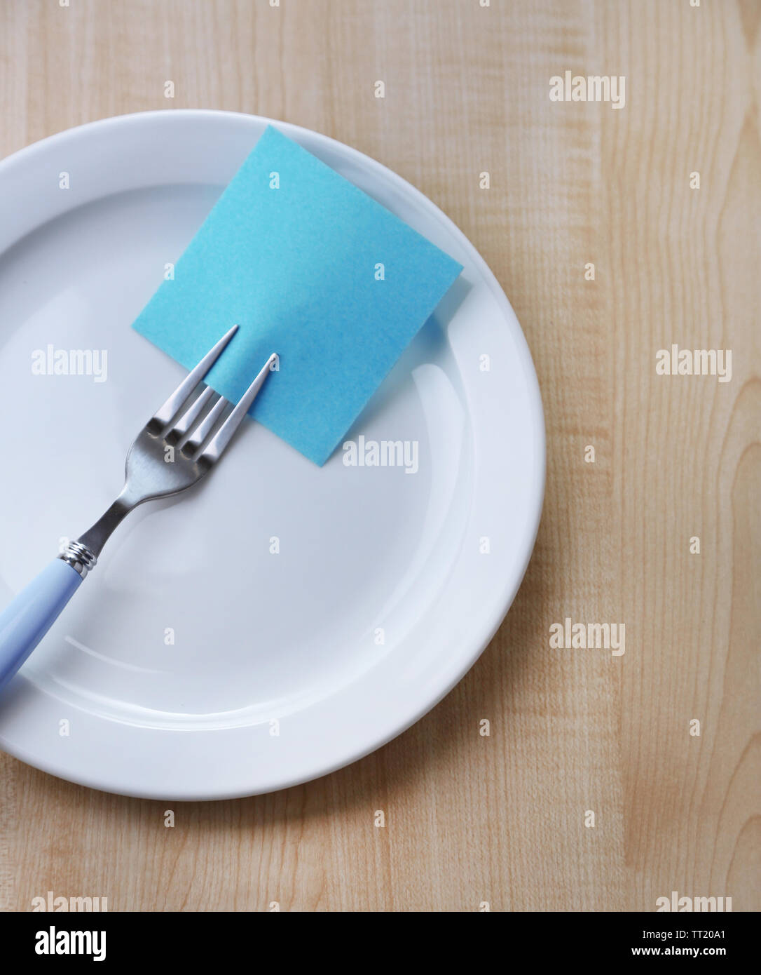 Empty note paper attached to fork, on plate, on color wooden background ...