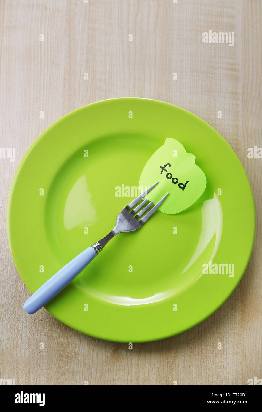 Note paper with message attached to fork, on plate, on color wooden ...