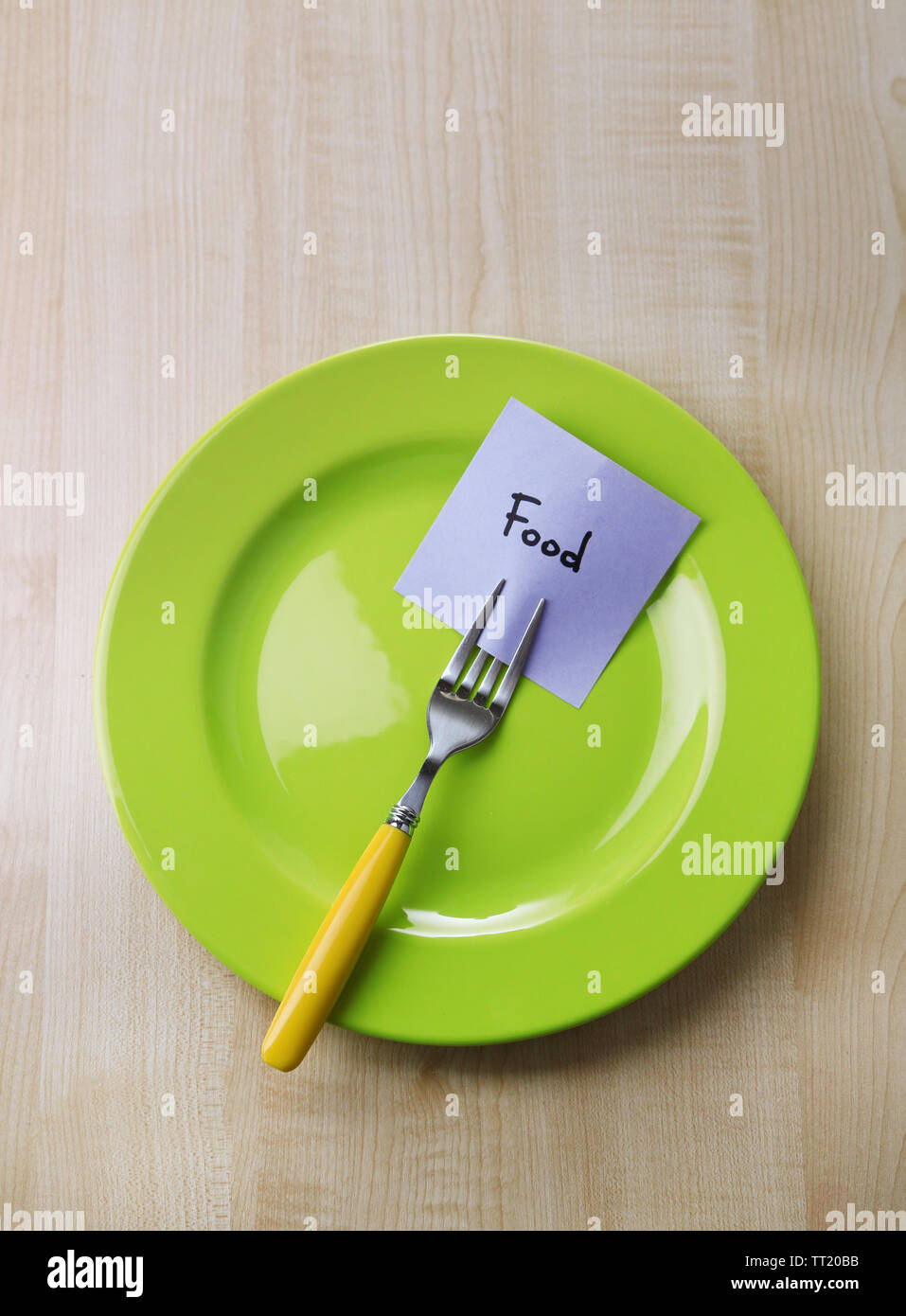 Note paper with message attached to fork, on plate, on color wooden ...