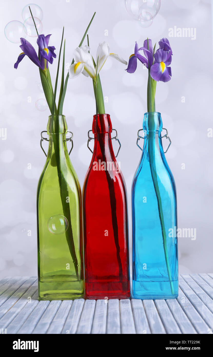 Beautiful irises and daffodils in bottles, on light background Stock ...