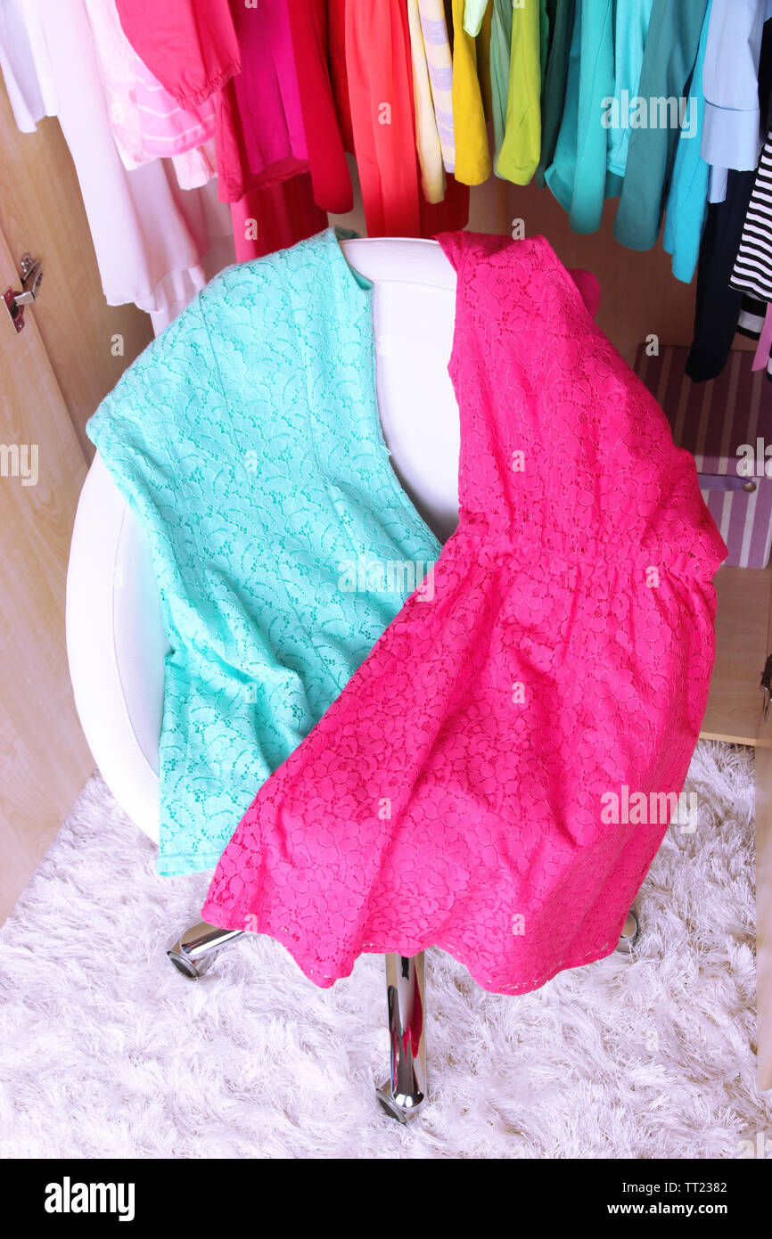 Female clothes in wardrobe and chair in room Stock Photo - Alamy