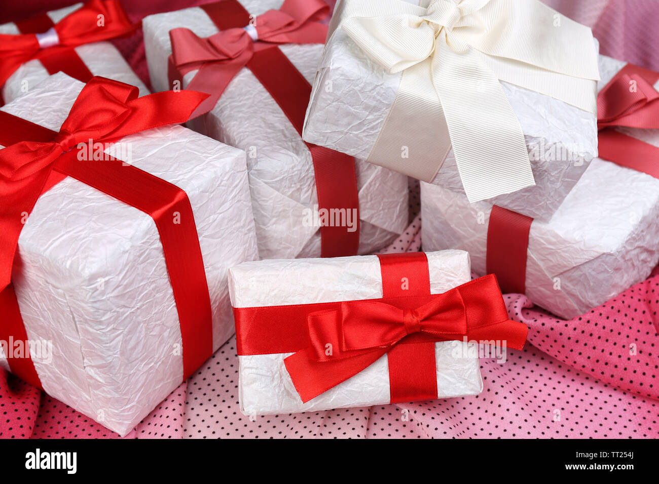 Beautiful gifts with red ribbons on pink cloth Stock Photo - Alamy