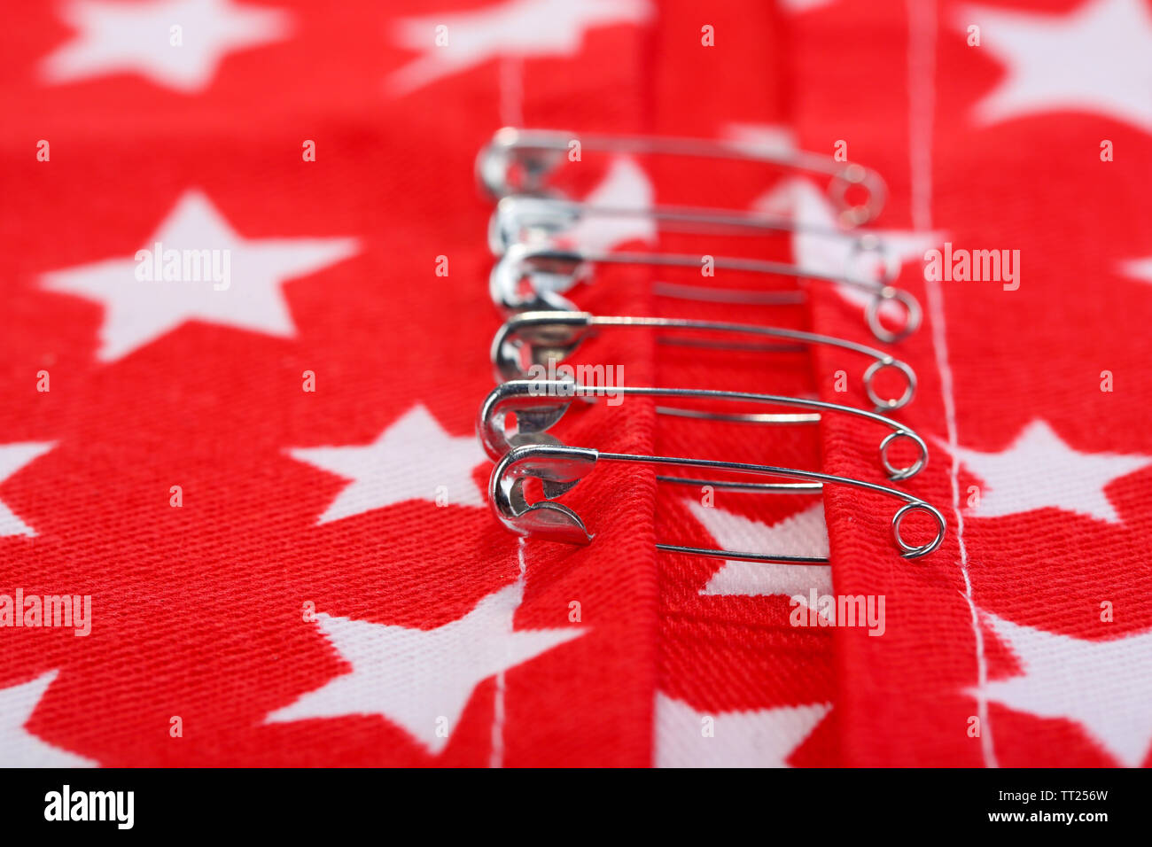 Safety pins on fabric background Stock Photo - Alamy