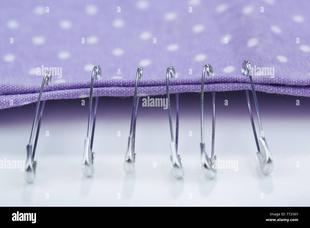 Safety pins on fabric background Stock Photo - Alamy