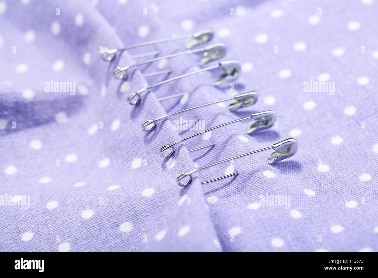 Safety pins on fabric background Stock Photo - Alamy