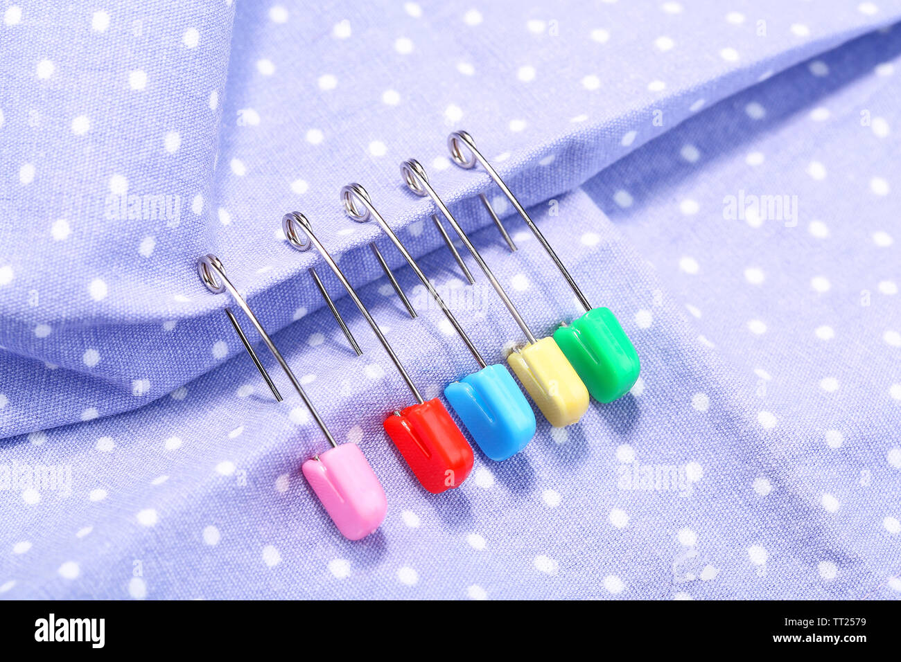 Safety pins on fabric background Stock Photo - Alamy