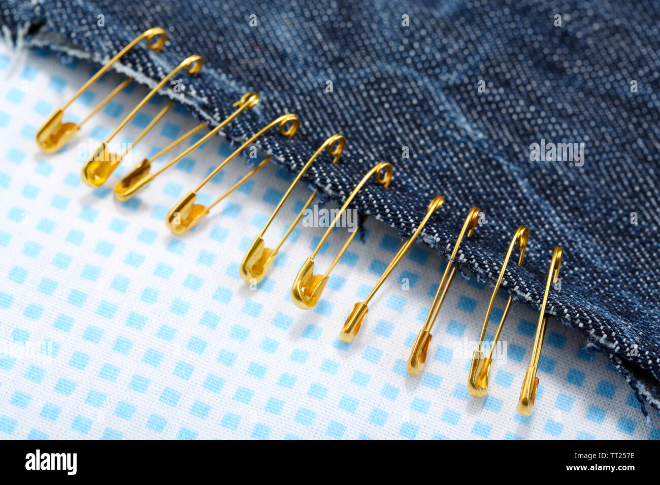 Safety pins on fabric background Stock Photo - Alamy