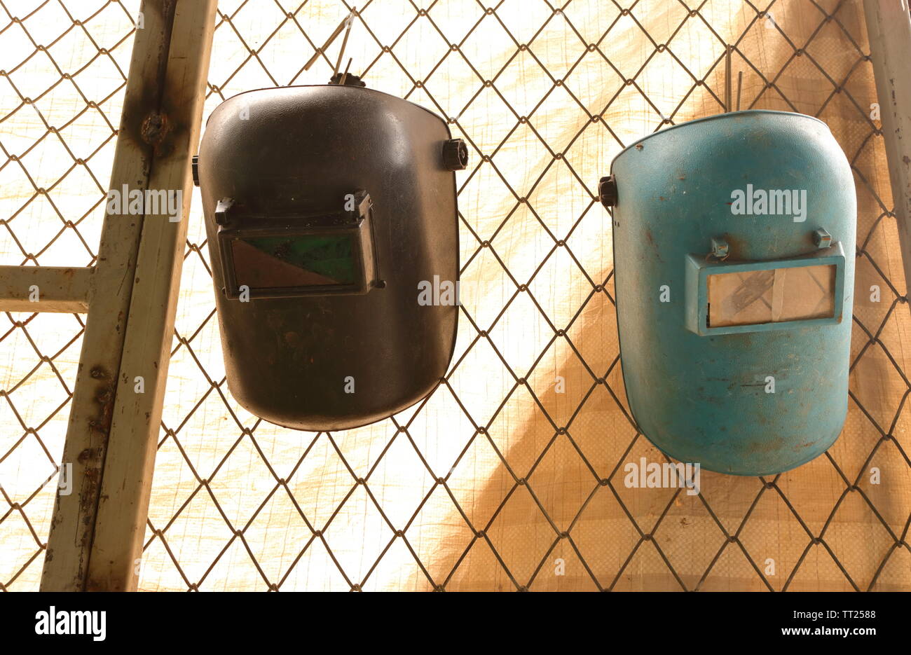 Closeup of welding masks hanging on the fence of working area, safety ...