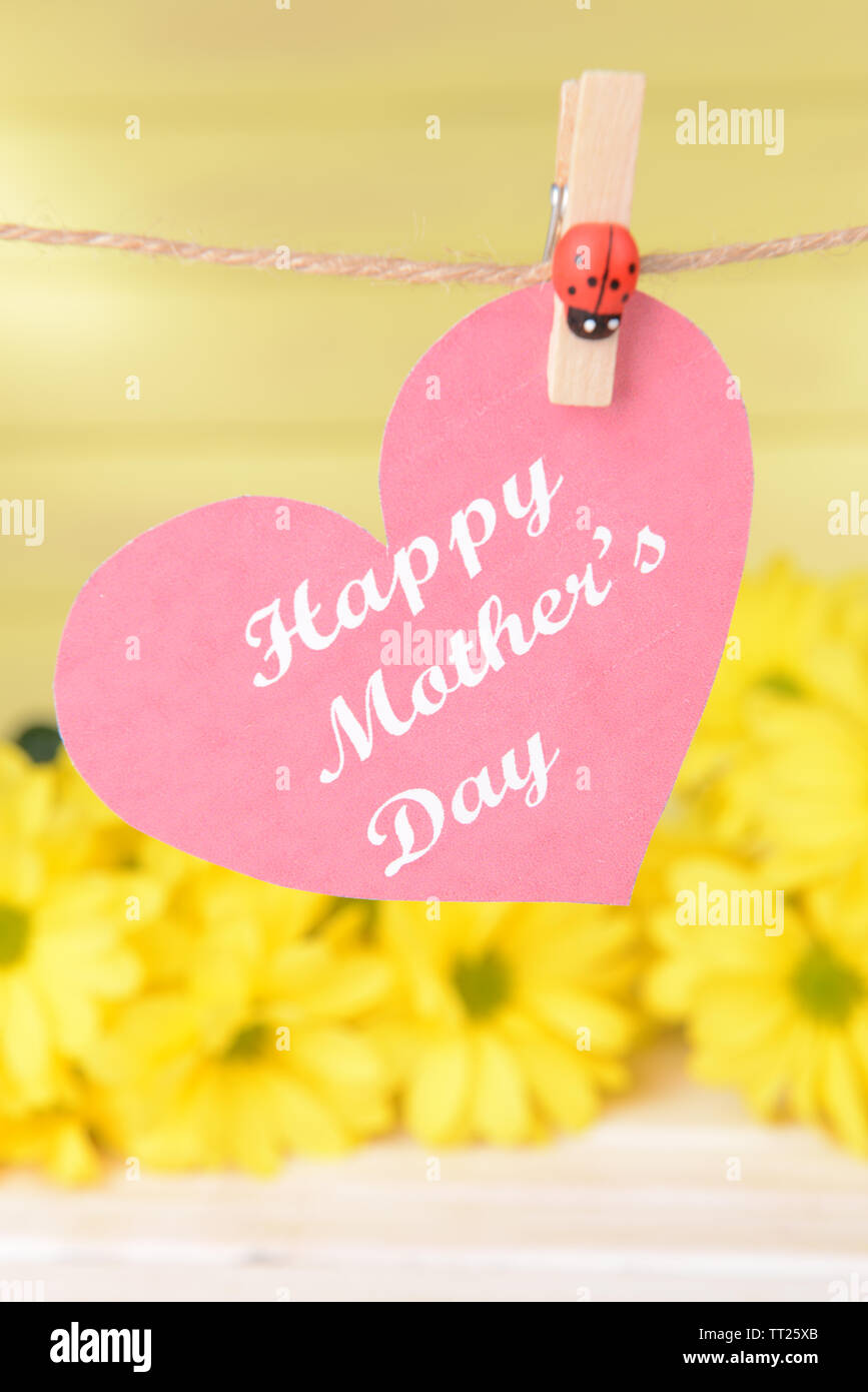 Happy Mothers Day message written on paper heart with flowers on yellow ...