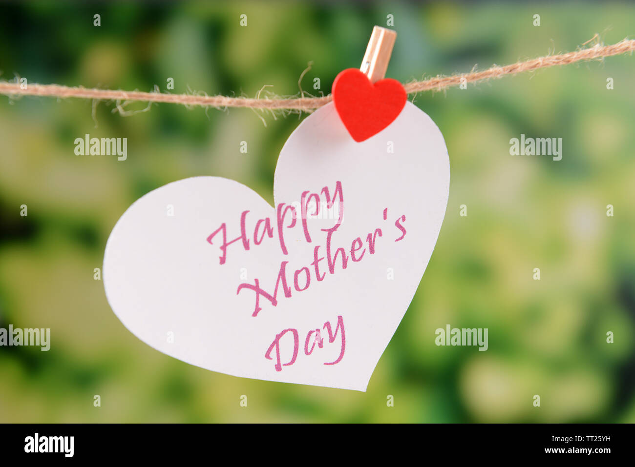 Happy Mothers Day message written on paper heart with flowers on bright ...