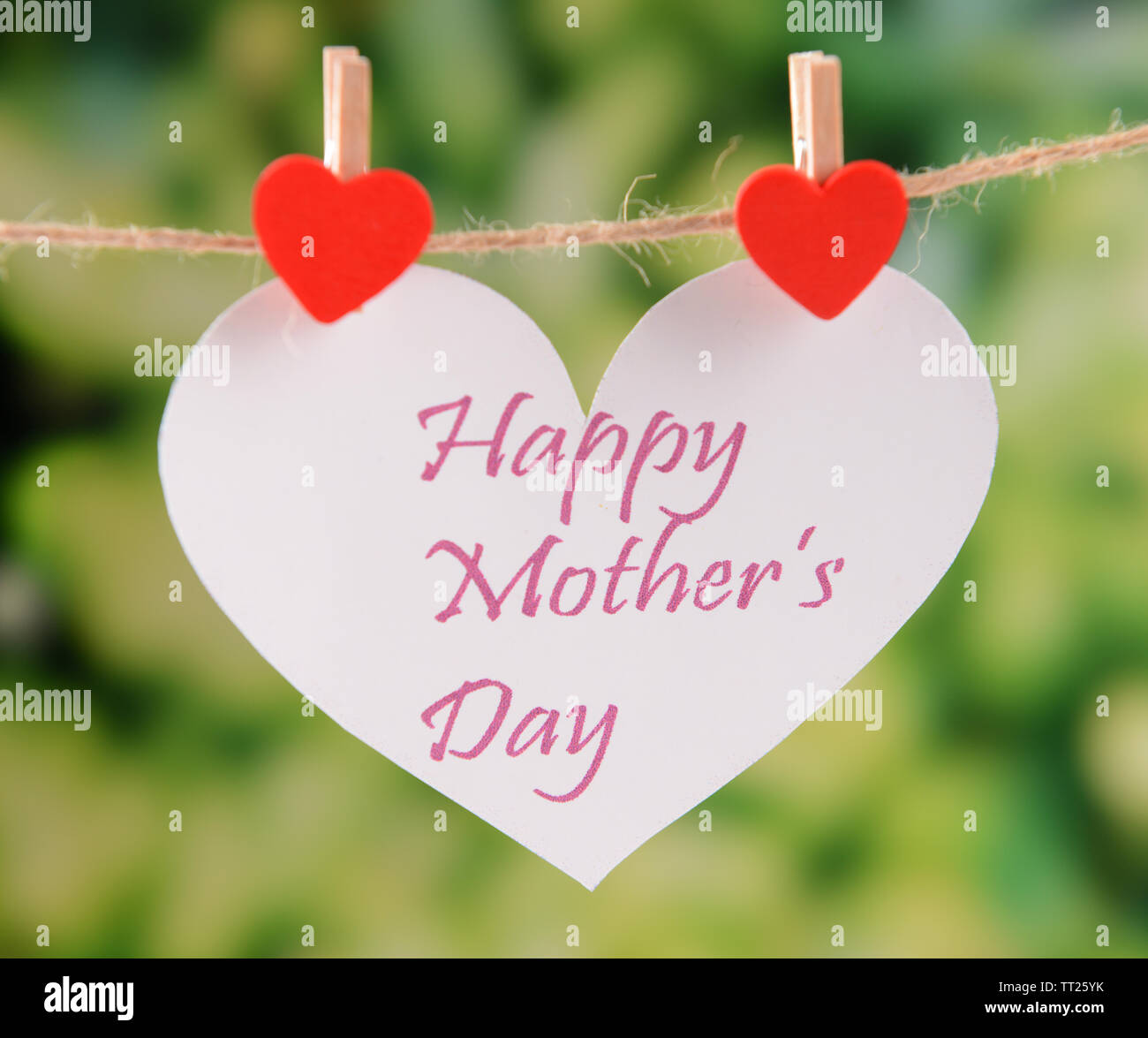 Happy Mothers Day message written on paper heart with flowers on bright ...