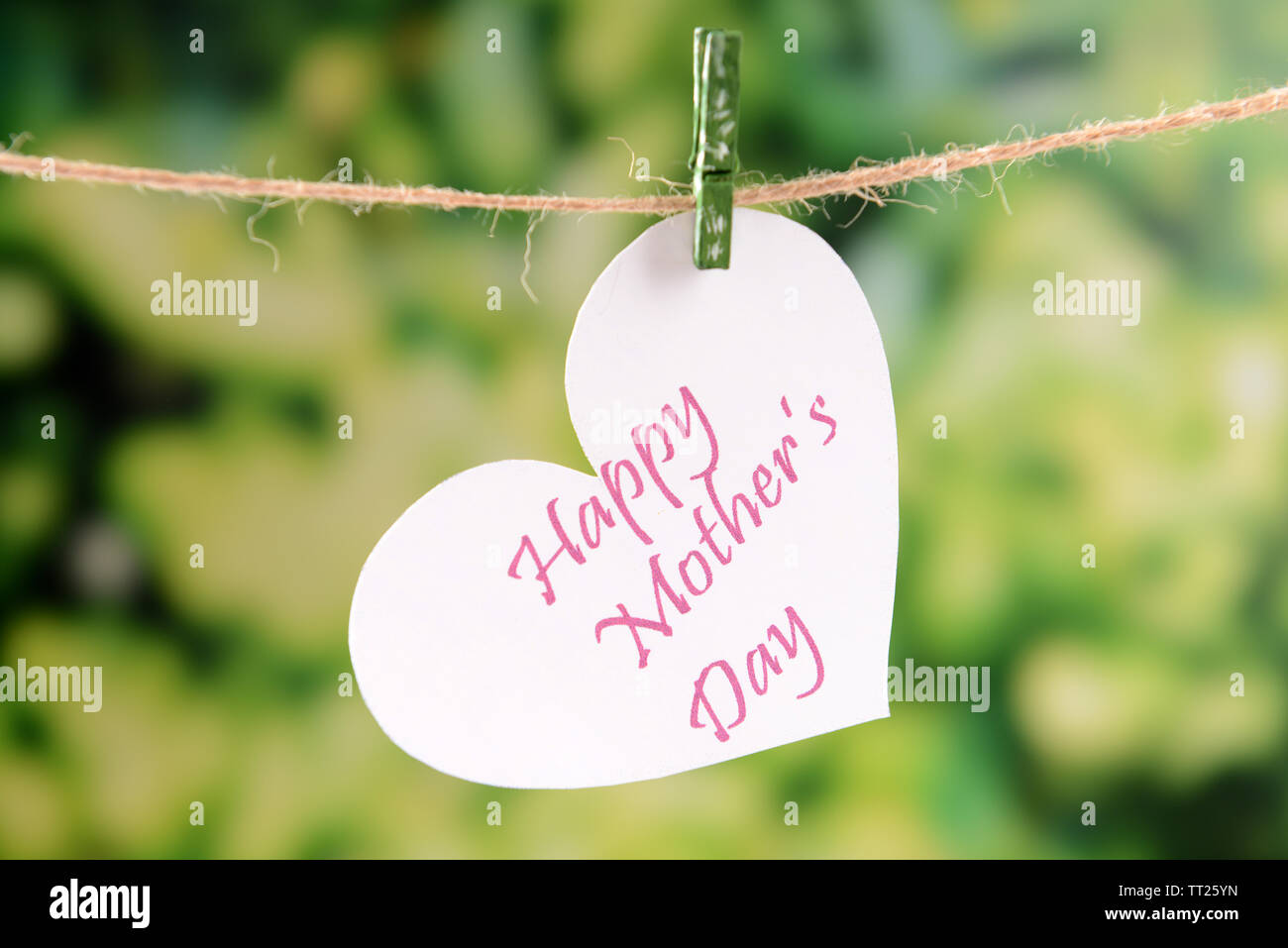 Happy Mothers Day message written on paper heart with flowers on bright ...