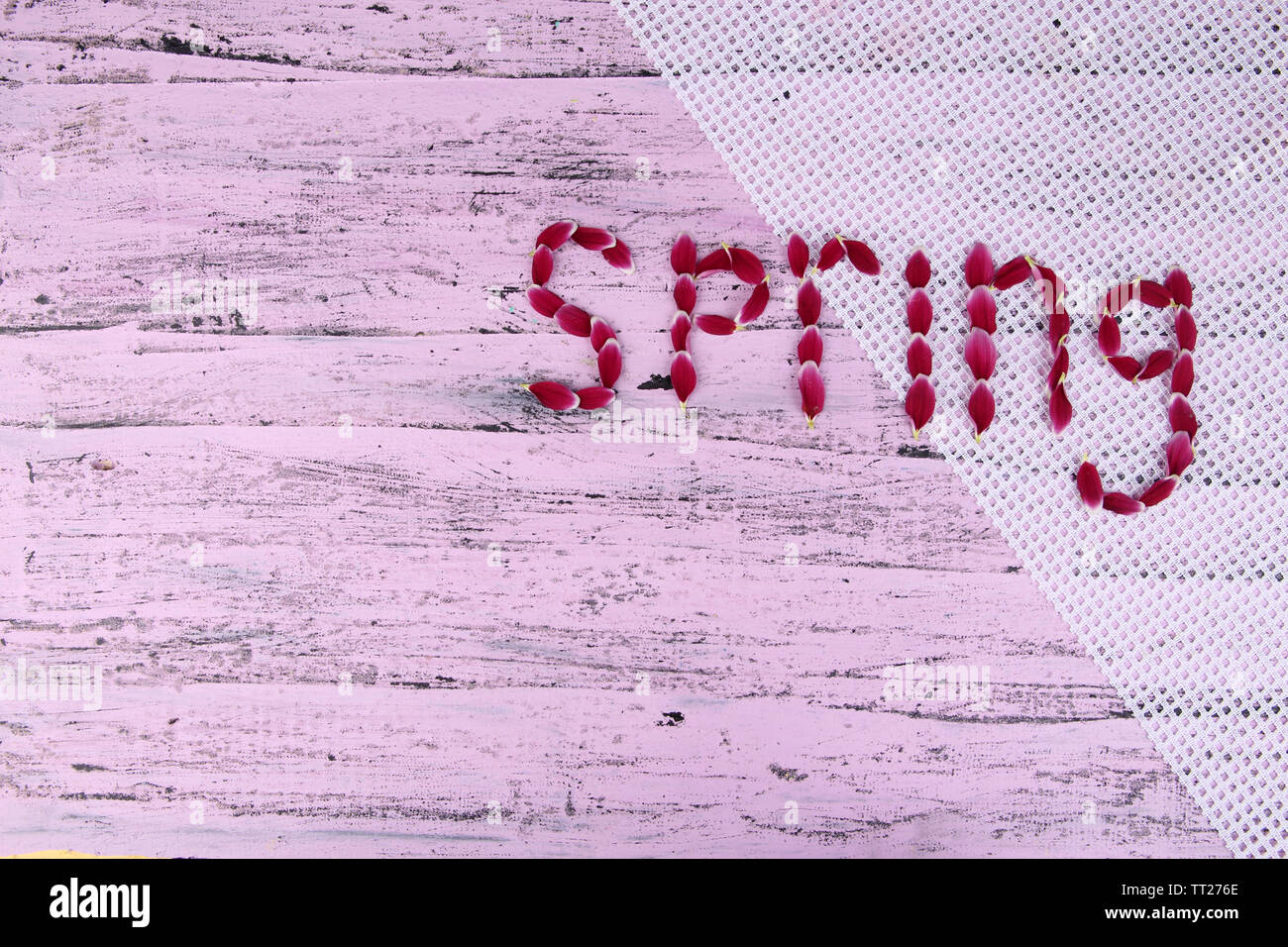 Romantic spring letters made of pink petals, on color wooden background ...