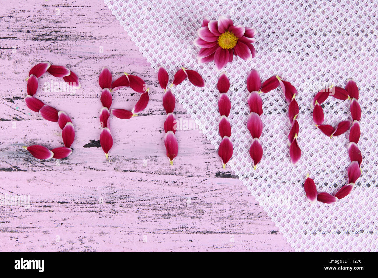 Romantic spring letters made of pink petals, on color wooden background ...