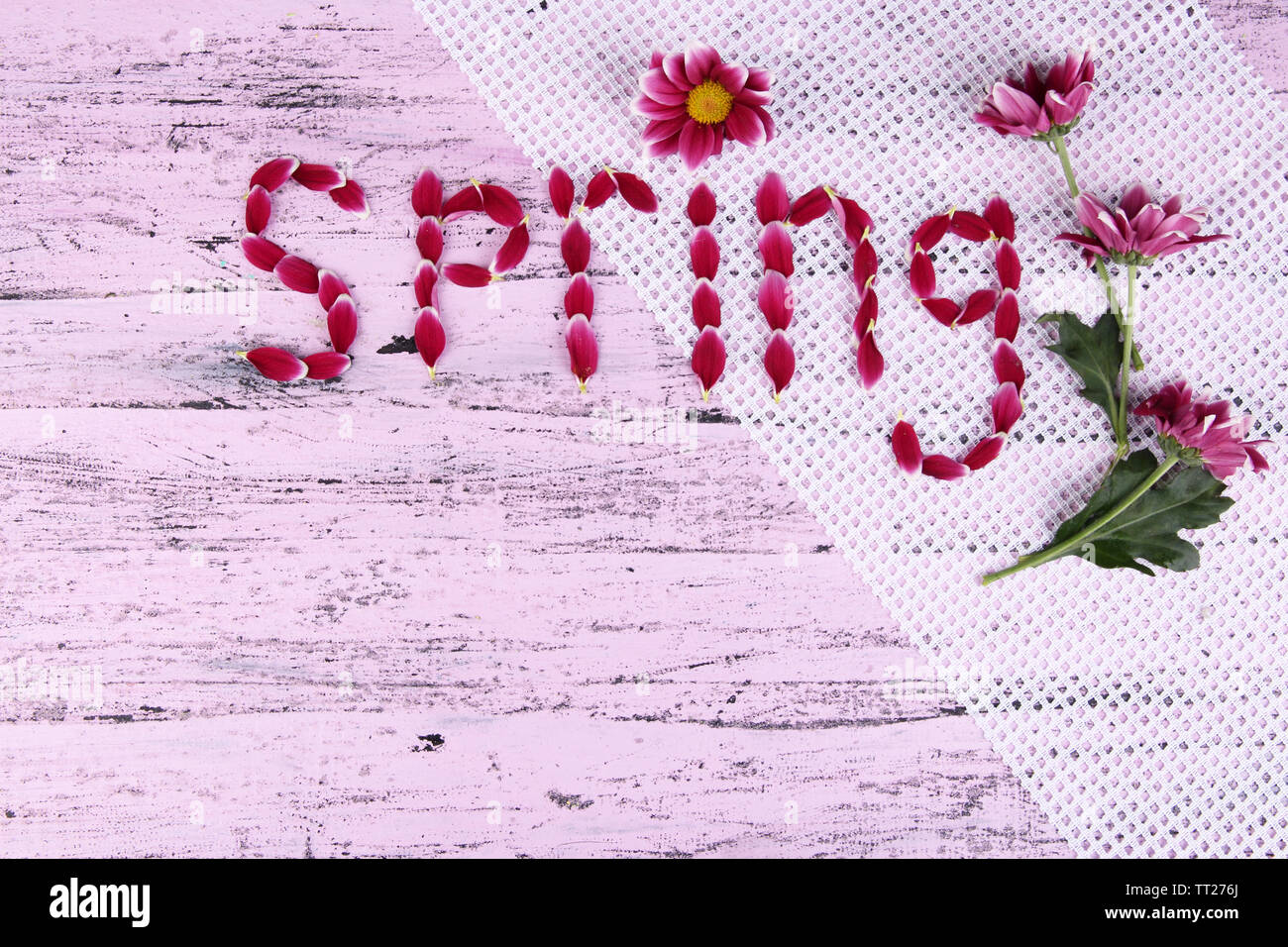 Romantic spring letters made of pink petals, on color wooden background ...