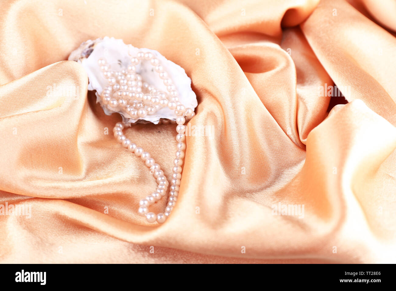 Beautiful pearls in shell on golden silk cloth Stock Photo - Alamy