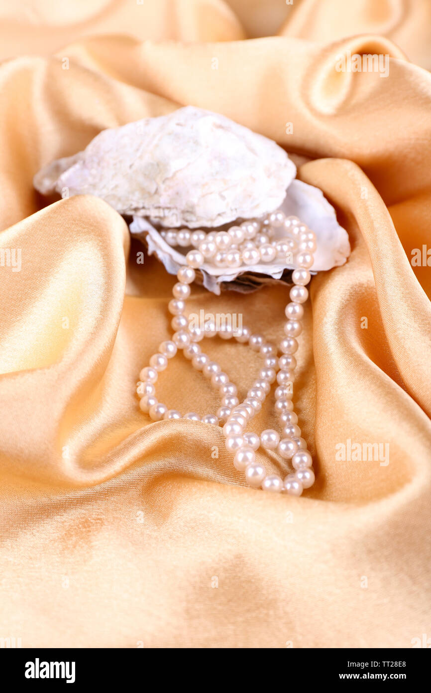 Beautiful pearls in shell on golden silk cloth Stock Photo - Alamy