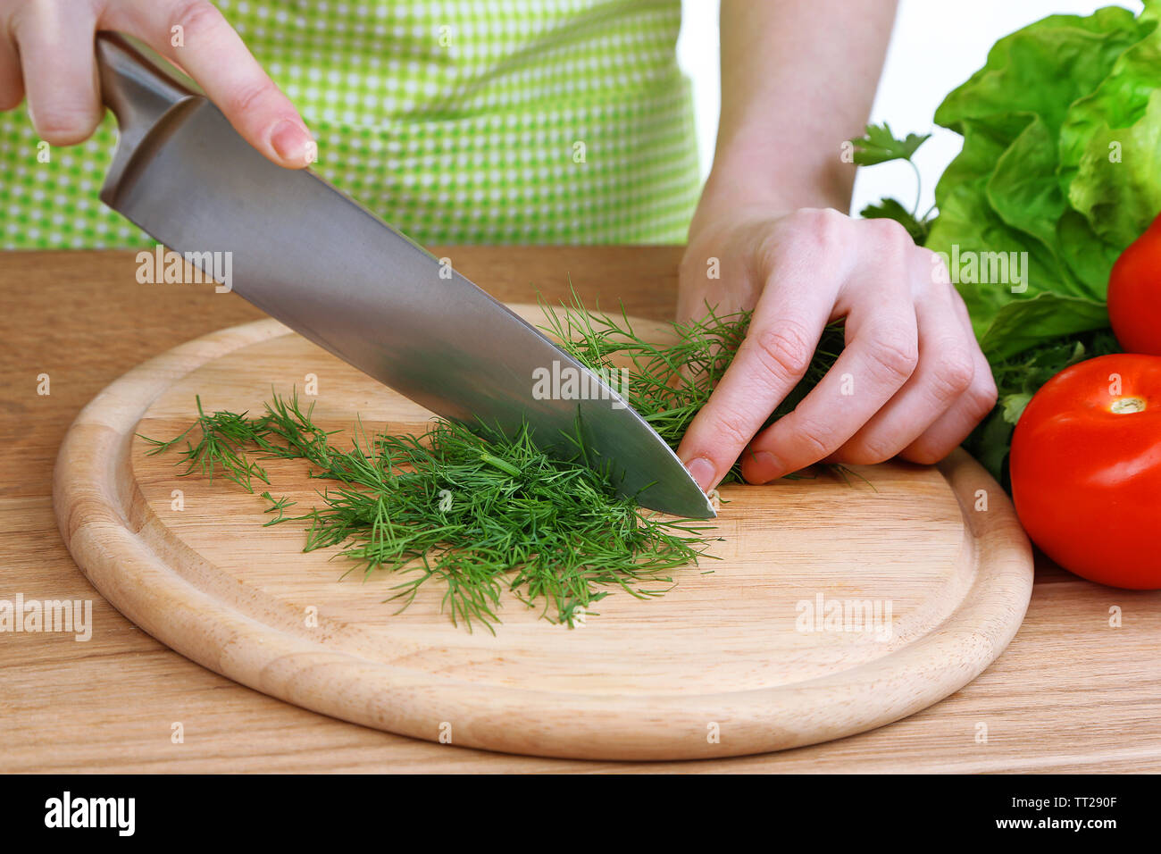 Female hands chopping dill on wooden board, close-up, isolated on white ...