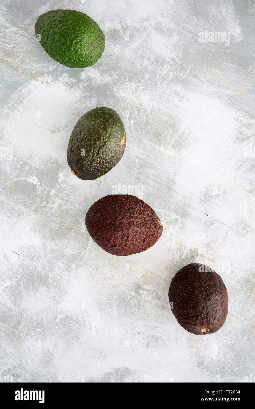 Four avocados in stages of ripening on rustic wooden background in flat ...