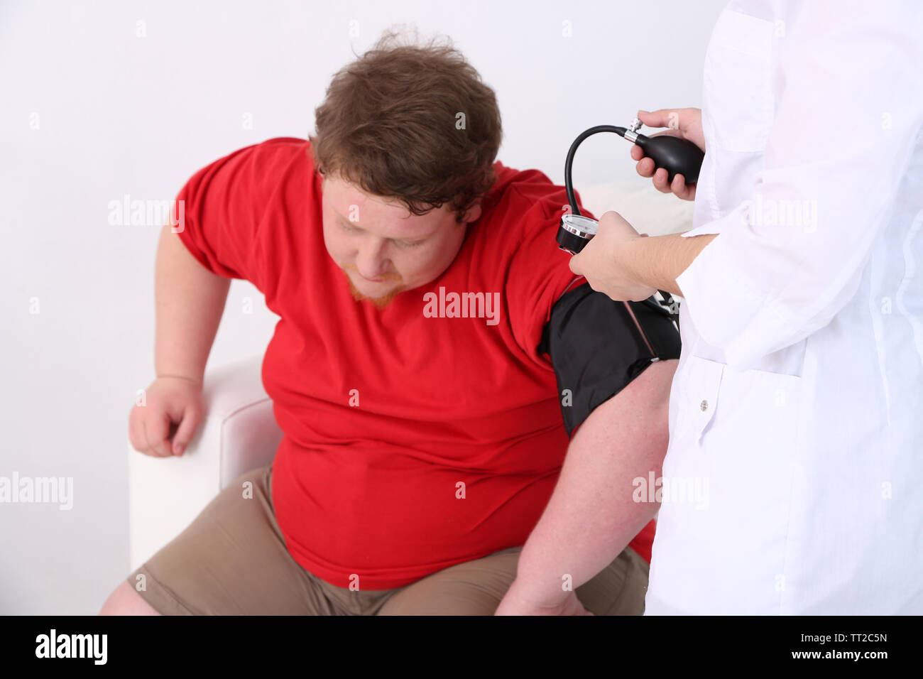 Doctor examining patient obesity on light background Stock Photo - Alamy