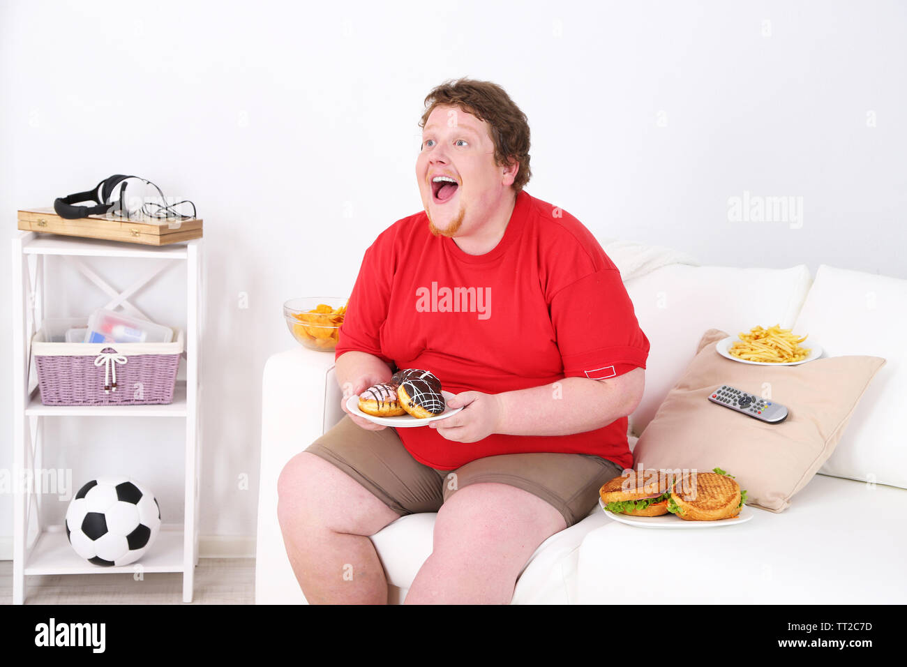 Overweight man eating food on couch hi-res stock photography and images ...
