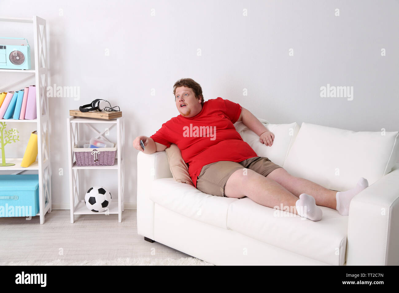 Lazy overweight male sitting on couch and watching television Stock ...