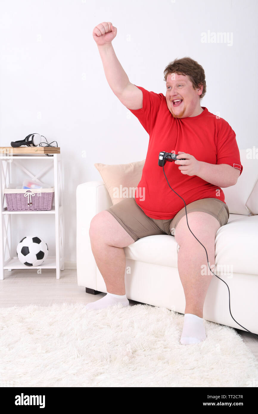 Fat man playing video games on home interior background Stock Photo - Alamy